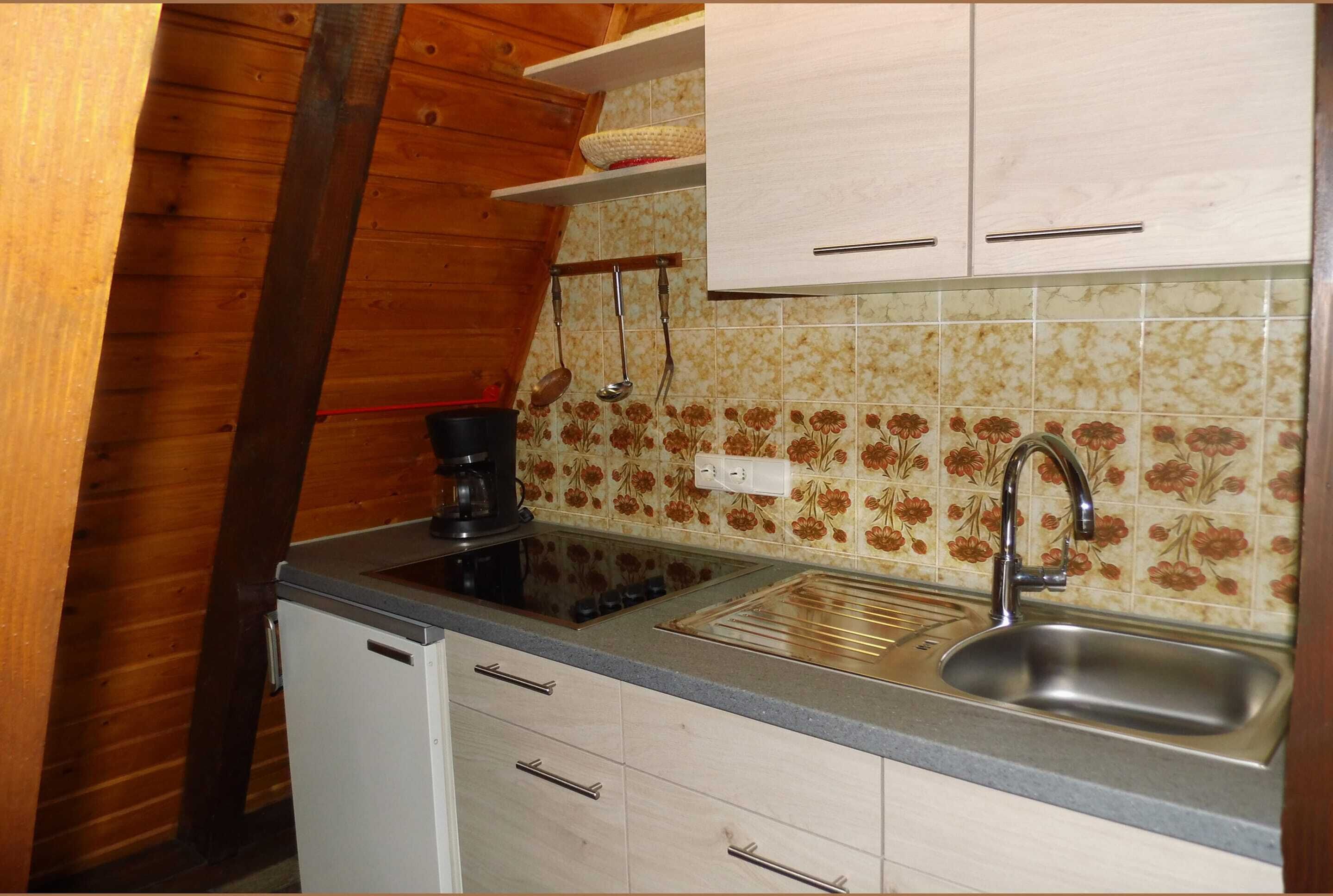 Cozinha com armários de madeira, pia de aço inoxidável e painel de azulejos.