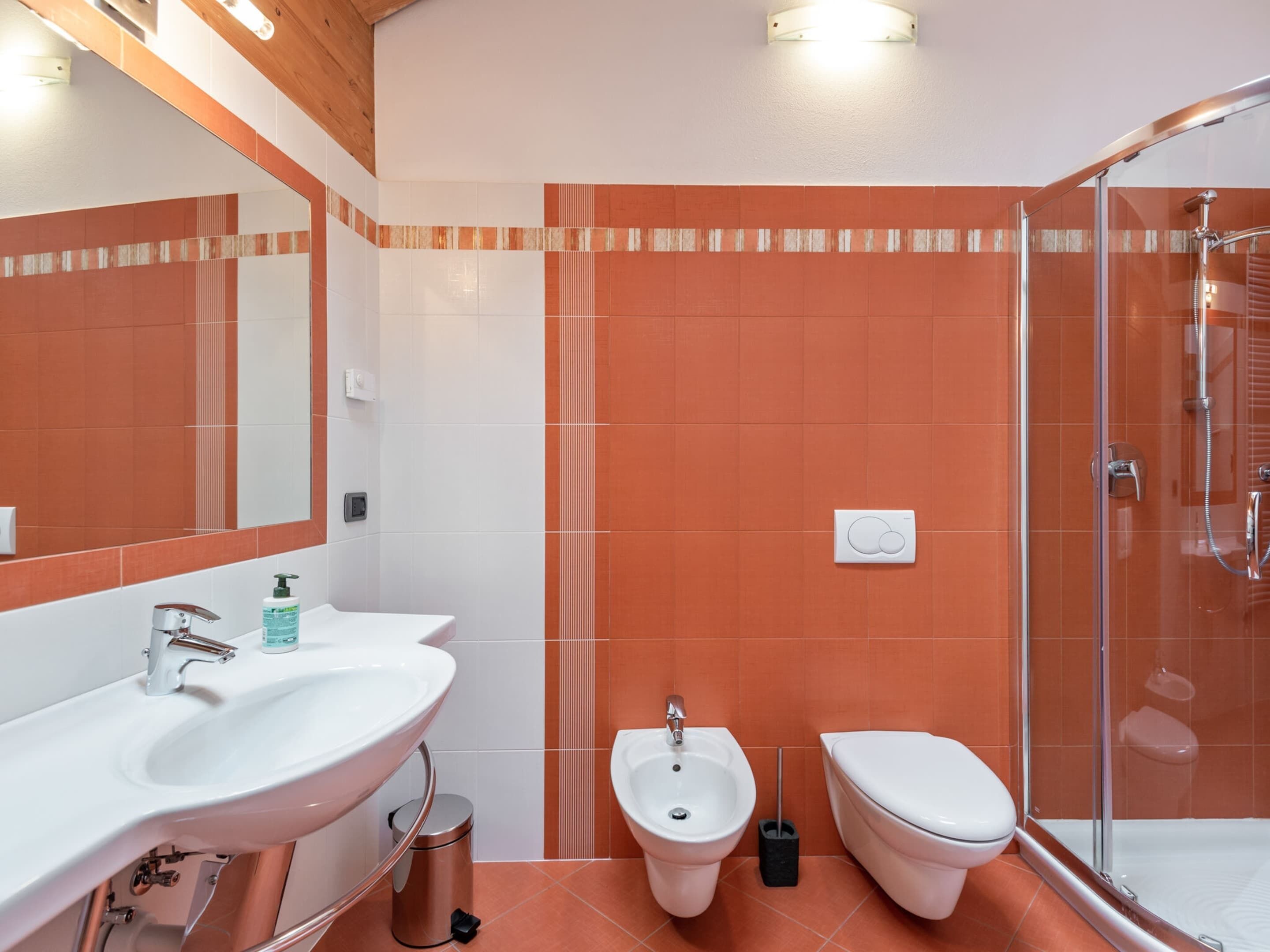 Uma casa de banho moderna com chuveiro, bidé e duas pias.