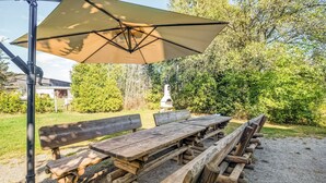 Uma mesa de piquenique com bancos, um toldo e uma estátua em um parque.
