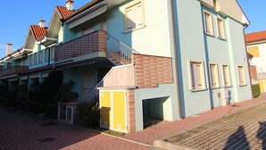 Um edifício de dois andares com varanda, uma pequena garagem anexa e fachada de tijolos.