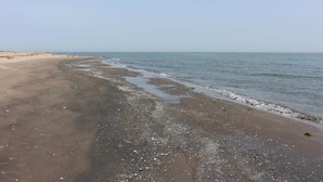 Uma praia com areal arenoso e águas calmas.