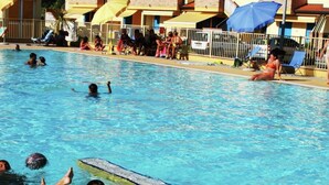 Piscina com pessoas na água e no deck.