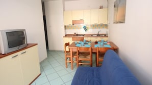 Um espaço compacto com cozinha compacta, área de refeições e sofá.