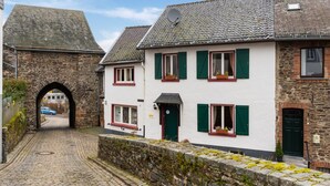 Uma rua de paralelepípedos que leva a uma fileira de edifícios tradicionais com paredes de pedra e telhados inclinados.