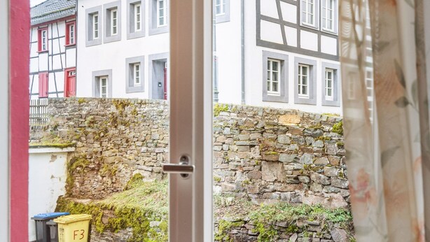 Visão através de uma porta de um edifício tradicional com paredes de pedra e estrutura de madeira.