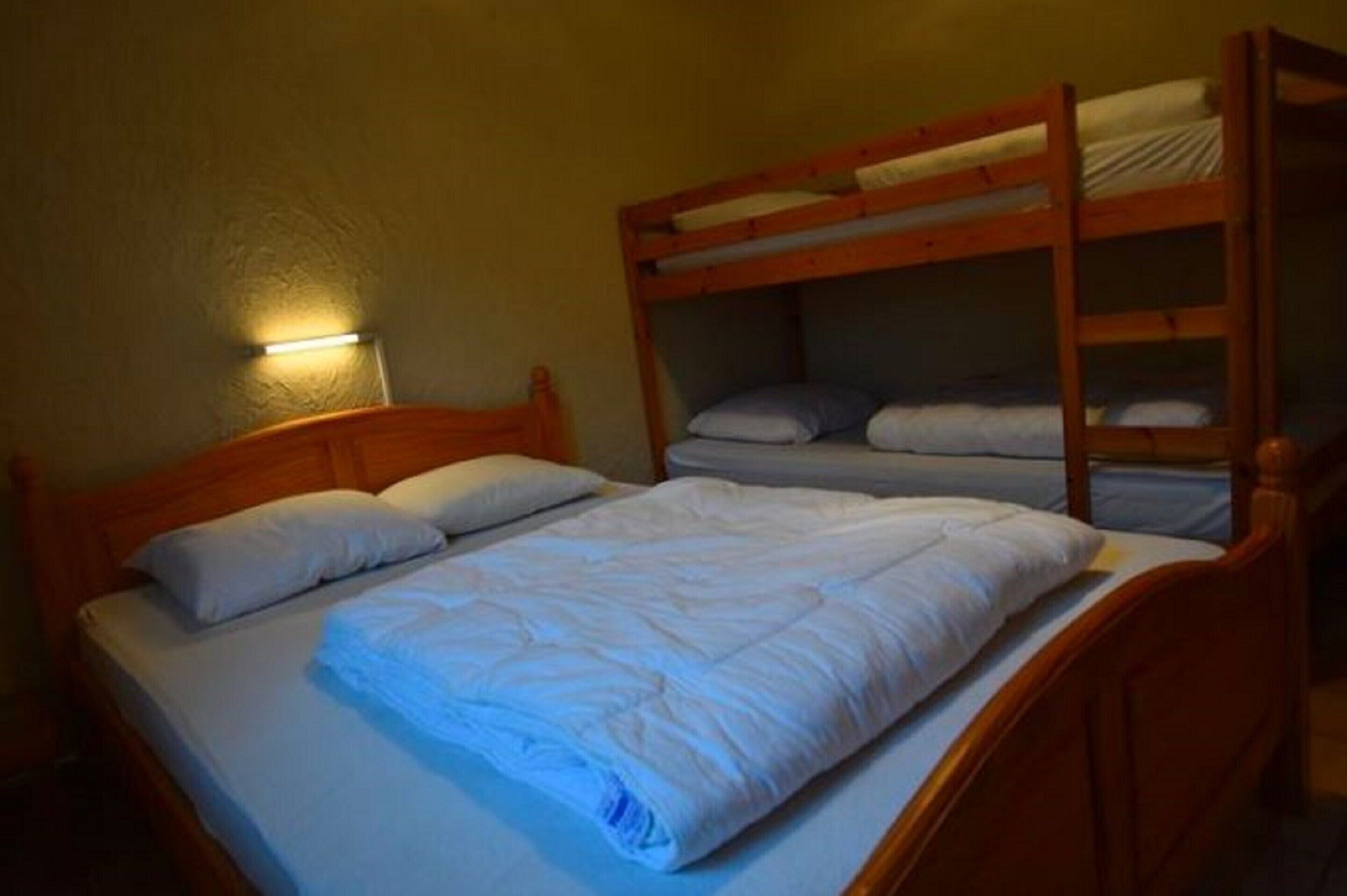 Uma cama de solteiro com cabeceira de madeira e uma cama beliche em cima.