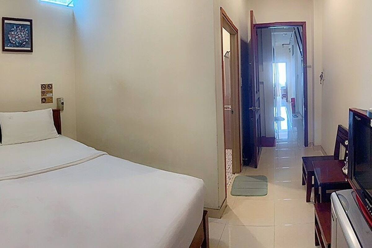 Quarto de hotel com uma cama grande, uma escrivaninha com cadeira e uma televisão.