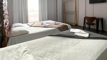 Quarto de hotel com duas camas, televisão e janela com cortinas.