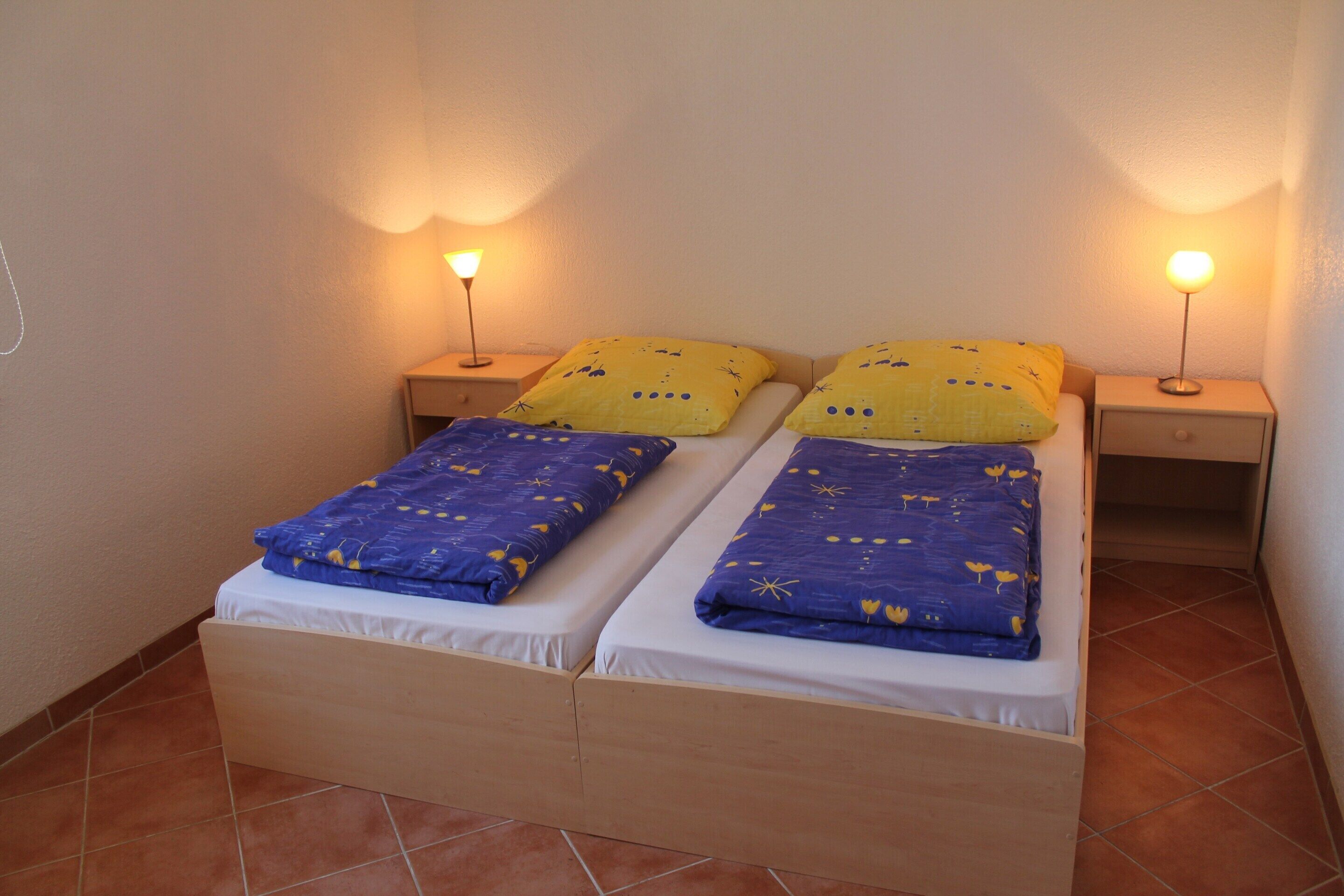 Uma cama de casal com duas mesas de cabeceira, cada uma com uma luminária.