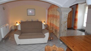Uma sala de estar com sofá, mesa de madeira e cortina estampada.