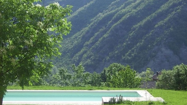 Piscina com vista para colinas verdes ao fundo.