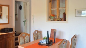 Uma sala de jantar com uma mesa de madeira, cadeiras e uma janela decorada.