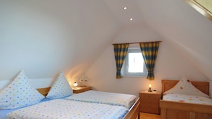 Quarto com cama, duas mesas de cabeceira, janela com cortinas e cabeceira de madeira.