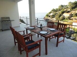Uma área de refeições com uma mesa posta para quatro pessoas, com vista para a costa.