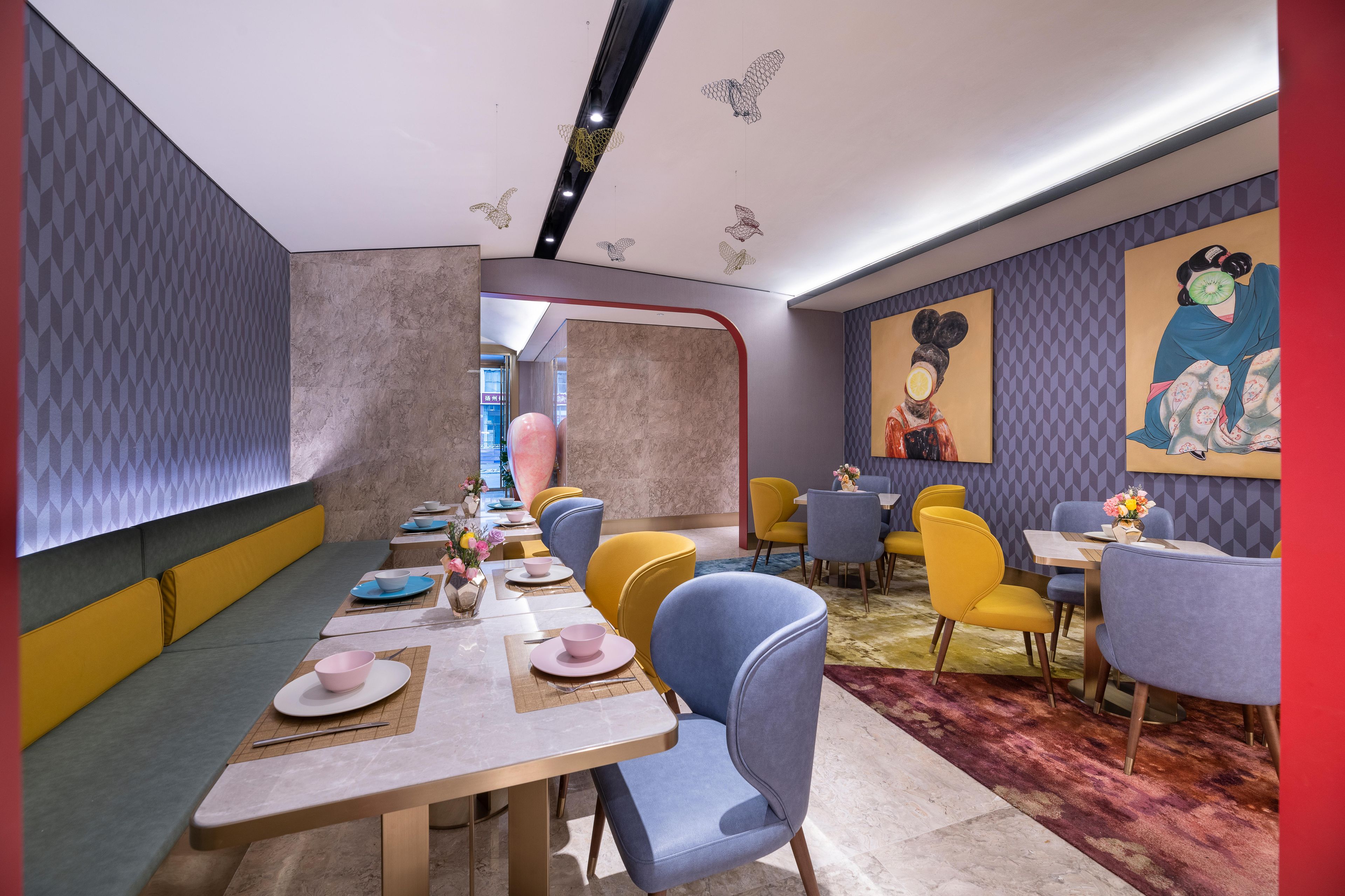 Interior de restaurante com uma longa mesa de jantar, várias cadeiras e um esquema de cores vibrante.