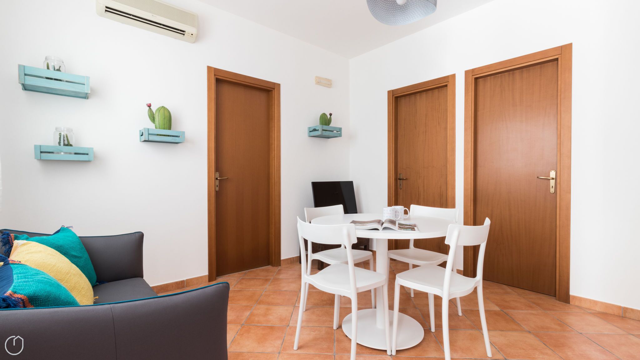 Um espaço compacto com sofá, uma mesa de jantar com cadeiras e duas portas de madeira.