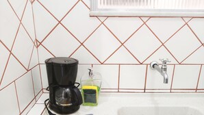 Uma cozinha com cafeteira, um frasco de detergente e utensílios de madeira no balcão.