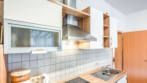 Cozinha moderna com armários brancos, exaustor de aço inoxidável e bancada de madeira.