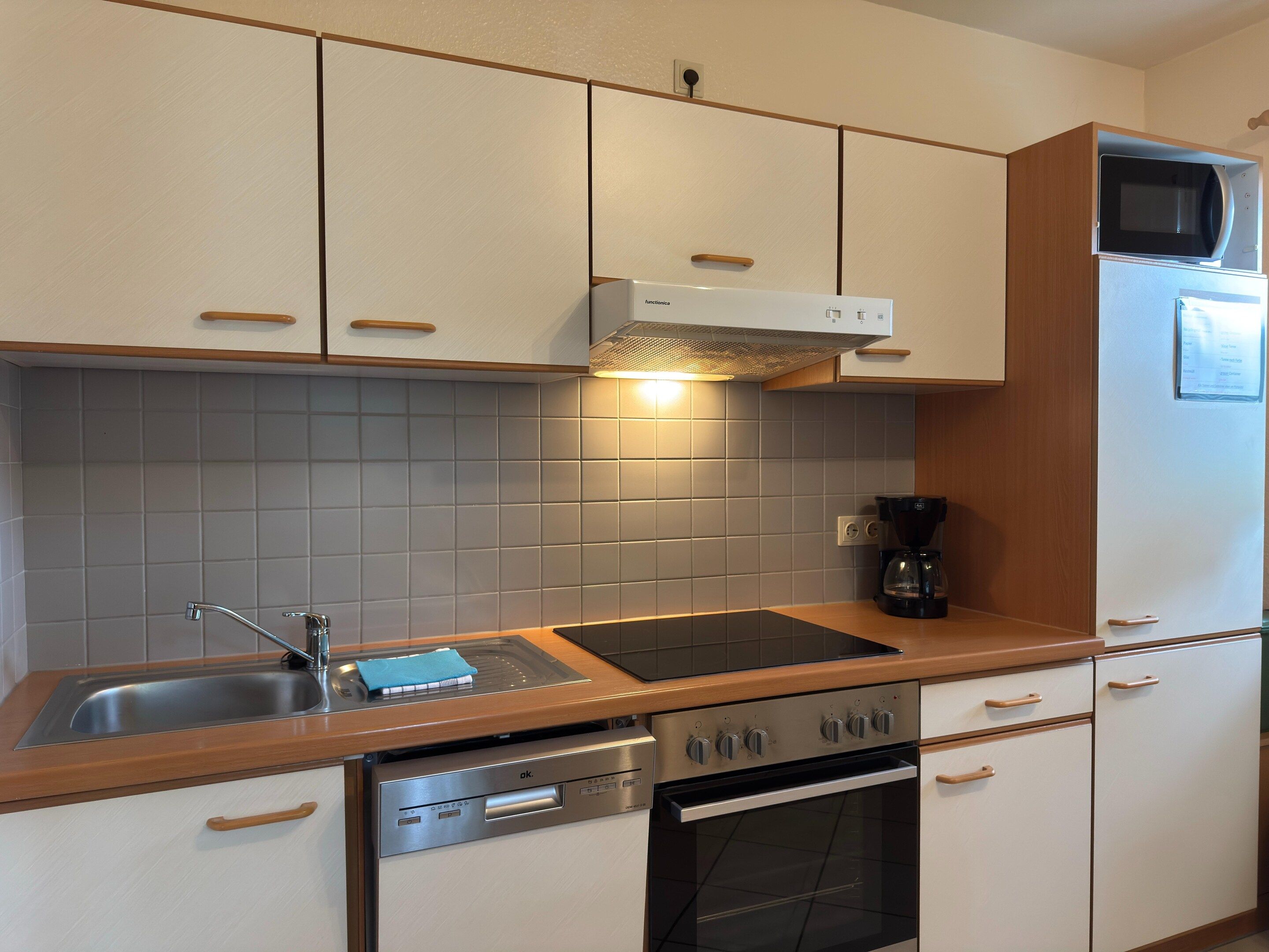 Uma cozinha compacta equipada com máquina de lavar louça, forno, micro-ondas e fogão embutido.
