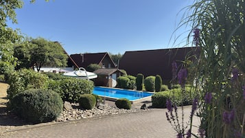 Uma área residencial com piscina, calçada pavimentada e jardins bem cuidados.