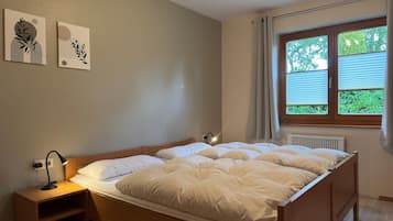 Quarto com cama de madeira, mesa de cabeceira com abajur e duas obras de arte penduradas na parede.