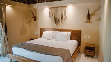 Quarto com cama de madeira, roupa de cama branca, decoração de macramé pendente e uma pequena mesa de cabeceira de madeira.