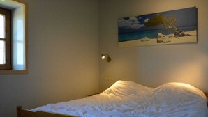 Uma cama de solteiro com cabeceira de madeira em um quarto com um quadro de uma praia na parede.