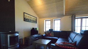Uma sala de estar com lareira, sofá, mesa de centro e televisão.