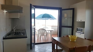 Uma cozinha com fogão a gás, micro-ondas e área de jantar com mesa e cadeiras.