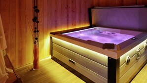 Um quarto de madeira com uma grande banheira de hidromassagem retangular, estrutura de madeira e base de metal.