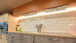 Uma cozinha moderna com painel de parede claro, eletrodomésticos de aço inoxidável e armários de madeira.