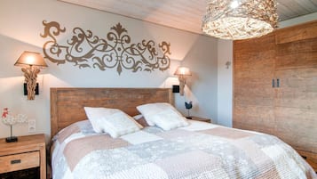 Quarto com uma cama grande, duas luminárias de cabeceira, um objeto decorativo na parede e um guarda-roupa de madeira.