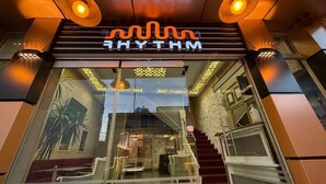 Entrada de hotel com um letreiro de neon que diz 'Rhythm'.