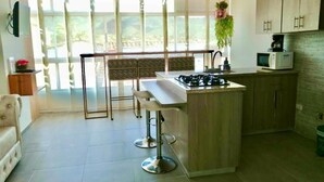 Cozinha moderna com ilha central, banquetas e vista através de grandes janelas.