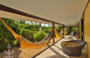 Um espaço coberto ao ar livre com redes e uma cadeira de vime.
