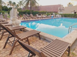 Uma piscina com espreguiçadeiras e uma estátua decorativa de peixe.