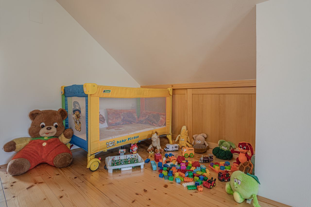 Quarto com parque infantil, um urso de pelúcia grande e vários brinquedos.