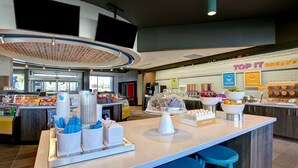 Uma zona de pequeno-almoço moderna com balcão, lugares sentados e uma variedade de alimentos.