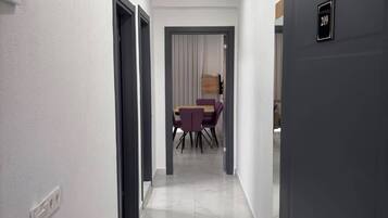 Um corredor com área de refeições, uma porta numerada e um interruptor de luz.