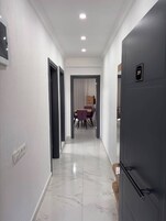 Um corredor com área de refeições, uma porta numerada e um interruptor de luz.