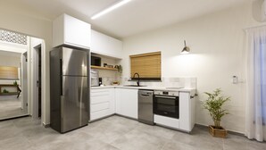 Uma cozinha moderna com armários brancos, eletrodomésticos de aço inoxidável e uma planta de bambu.