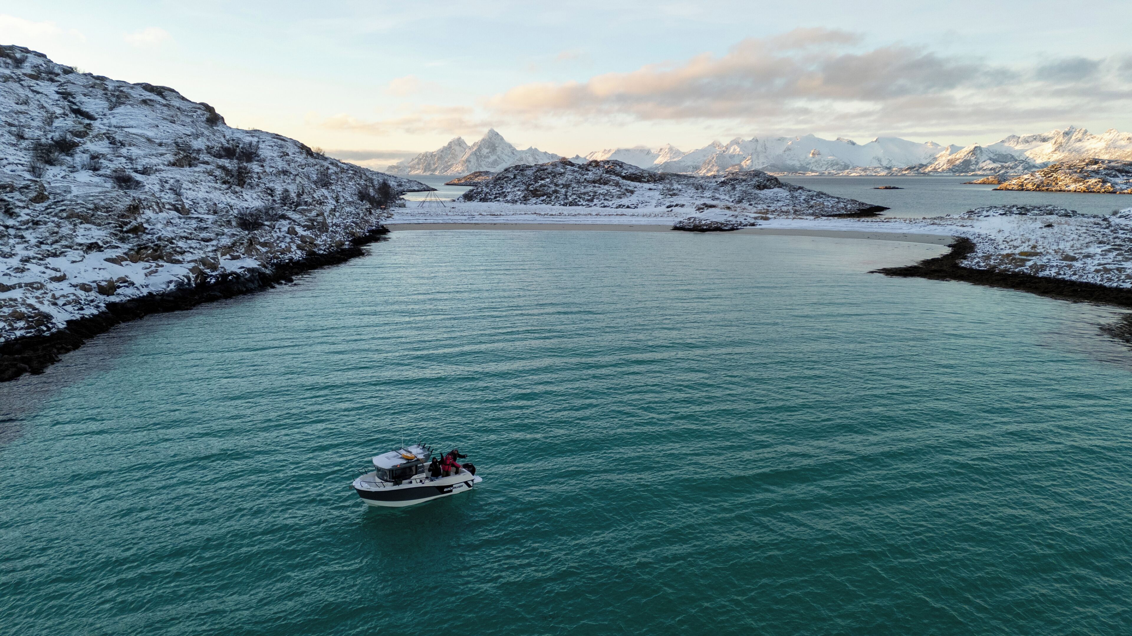 Um barco em águas calmas, cercado por montanhas cobertas de neve.