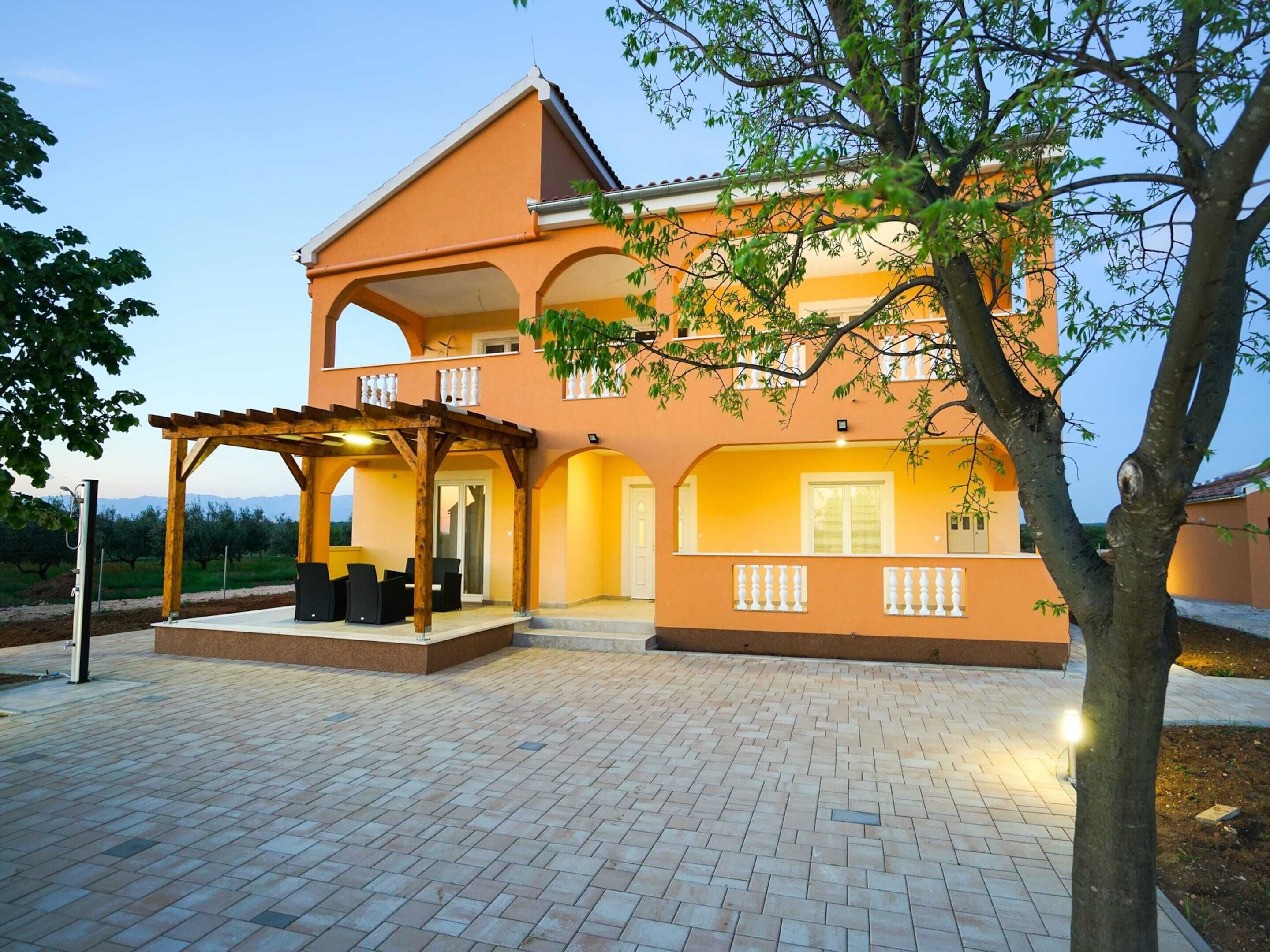 Uma casa de dois andares com varanda coberta, espaço para sentar ao ar livre e vista para a paisagem circundante.