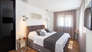 Quarto com cama grande, mesa de vidro, pintura na parede e televisão na parede.
