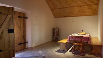 Um quarto com porta de madeira, uma mesa com toalha xadrez, um banco e teto rústico.
