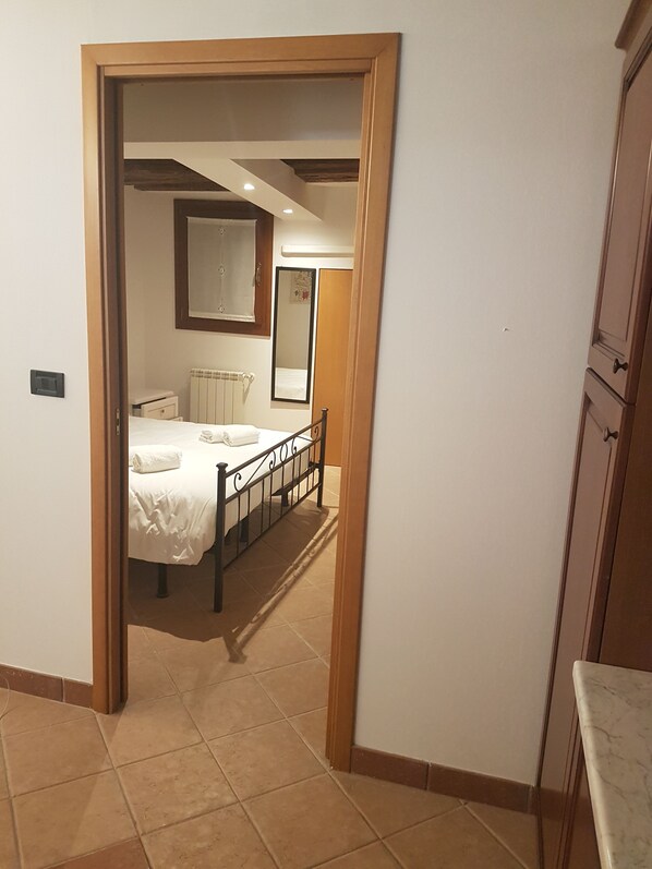 Quarto com cama, mesa de cabeceira, espelho e radiador.