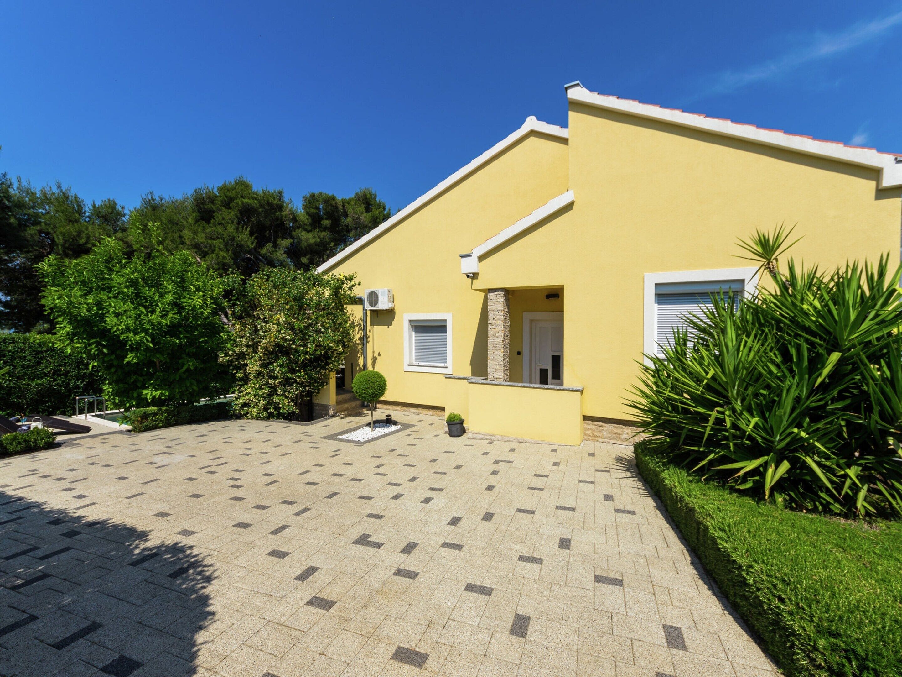 Um edifício amarelo com calçada pavimentada e um pequeno jardim.