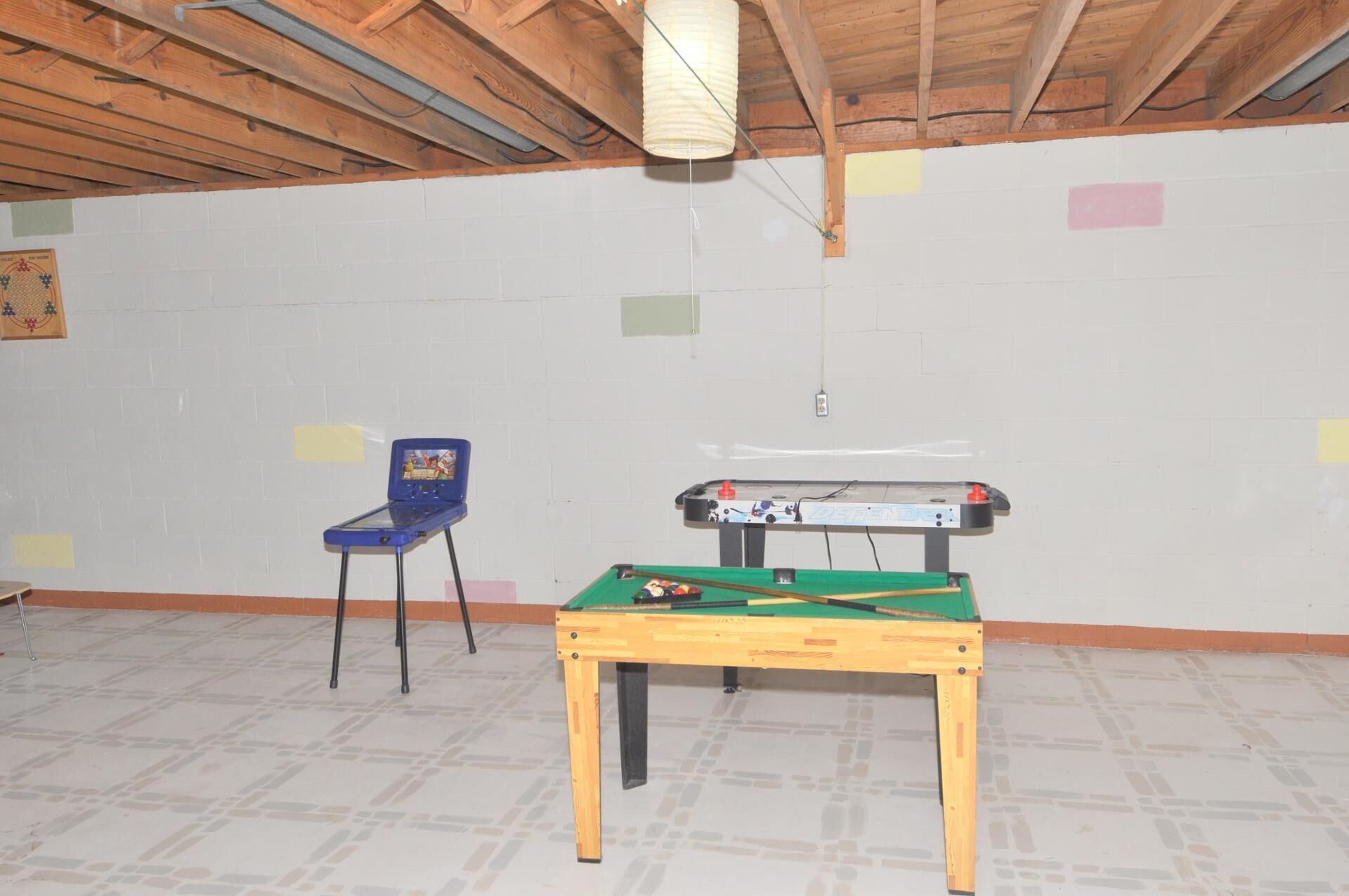 Quarto com mesa de madeira, mesa de futebol de mesa, uma cadeira azul e uma parede de tijolos brancos com alguns post-its coloridos.