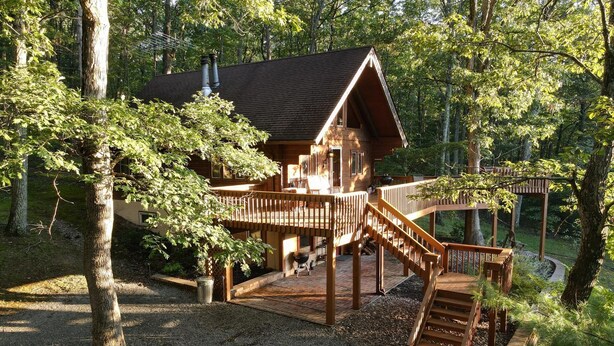 Uma cabana com um deck de madeira e uma escada que leva a um segundo andar.