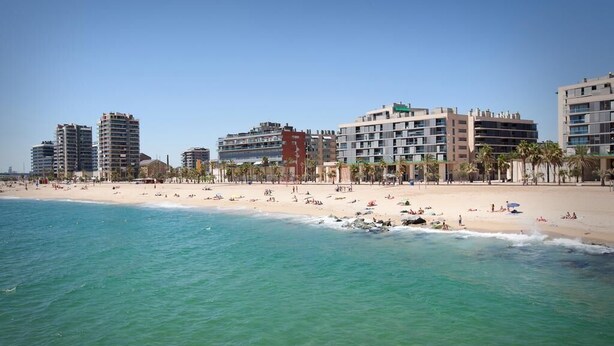 Uma praia com edifícios ao fundo.